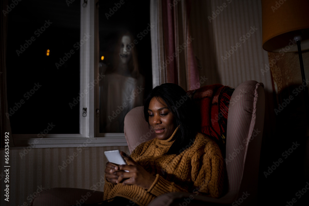 Ghost looking through window at woman using mobile phone in cabin Stock ...