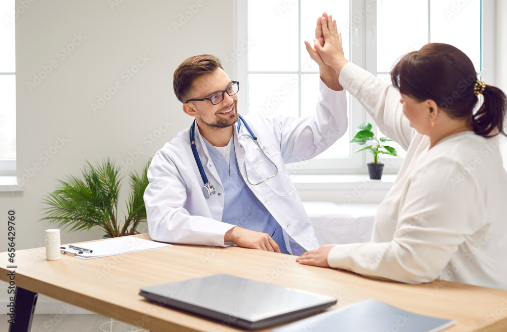 Portrait of a young happy male friendly doctor giving high five to a ...