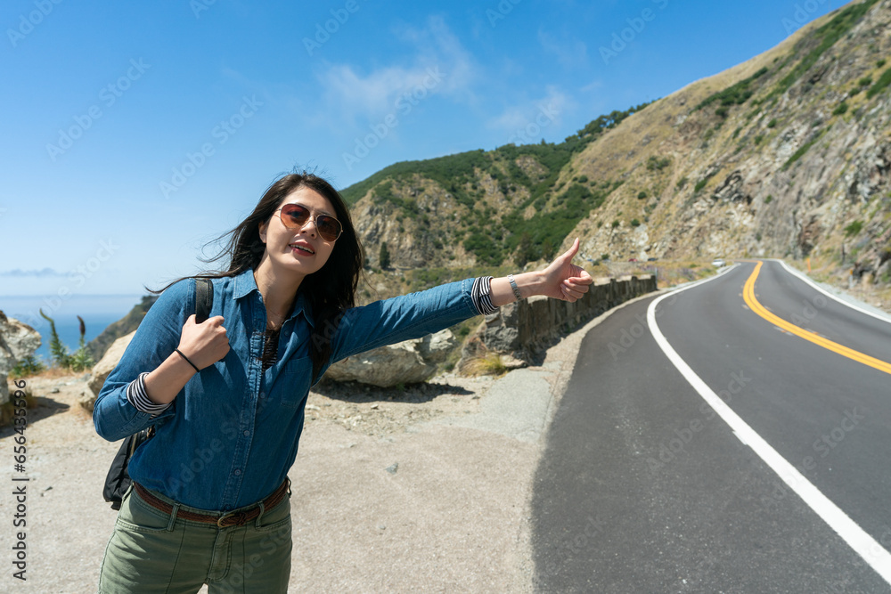 happy asian Japanese woman hitchhiker hailing a ride with thumb up hand ...