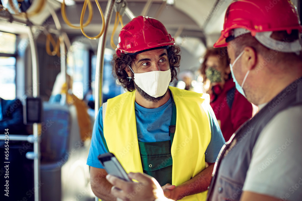 Two male construction workers commuting to work together on the bus ...