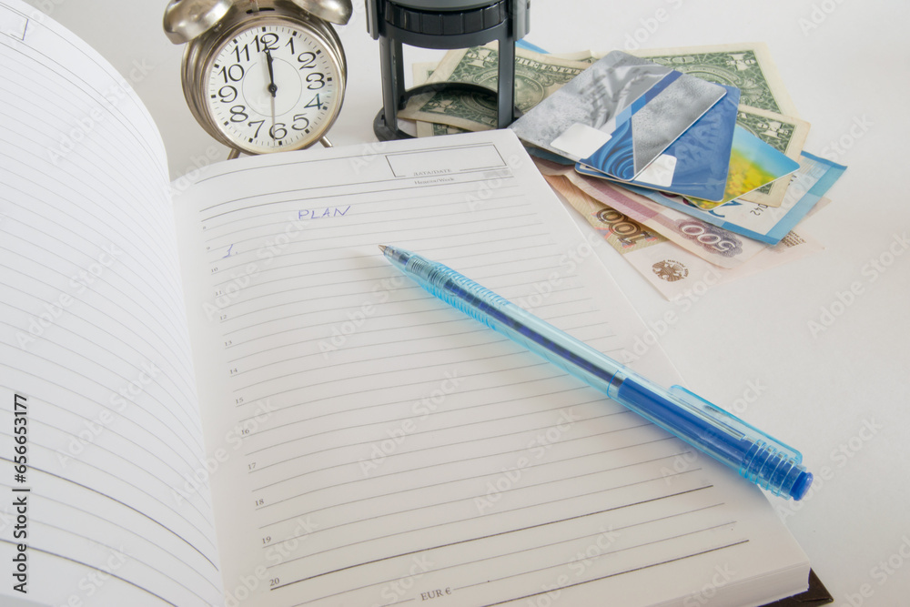 Notebook with the word plan on the office table with stationery, clock ...