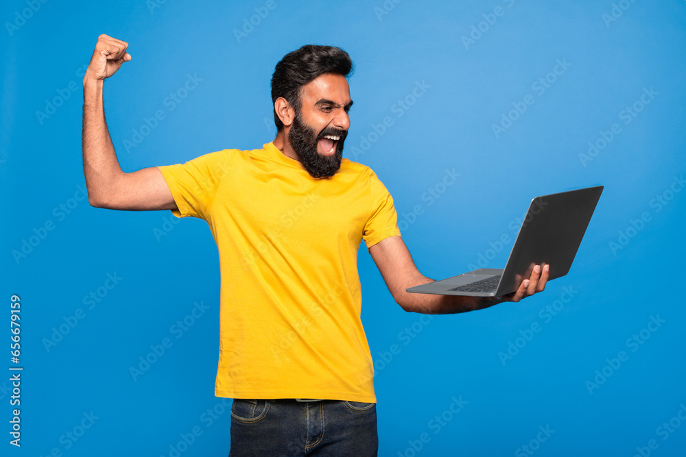 Joyful indian middle aged man holding laptop and celebrating success ...