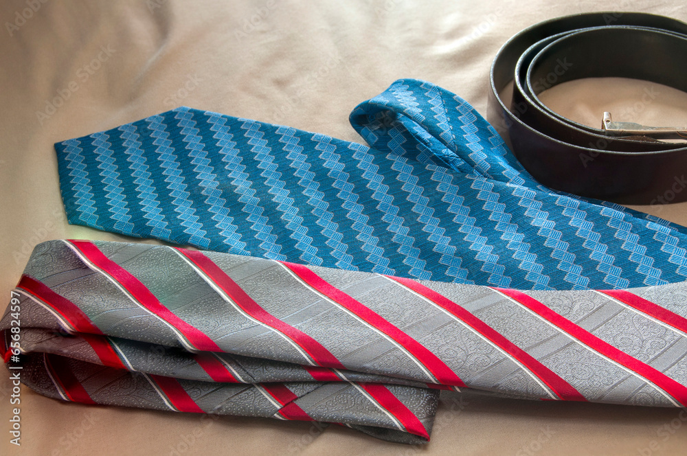 Silk blue necktie and gray with red tripes necktie on a bed with a ...