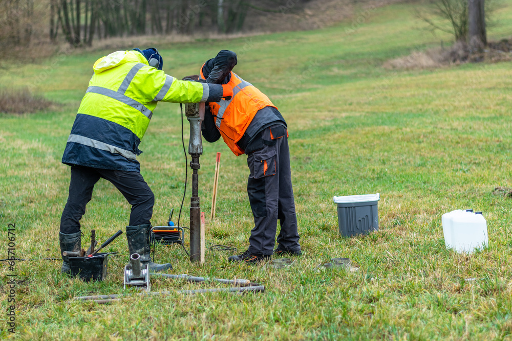 Workers using a soil sampling drill to get a core sample of the ground ...