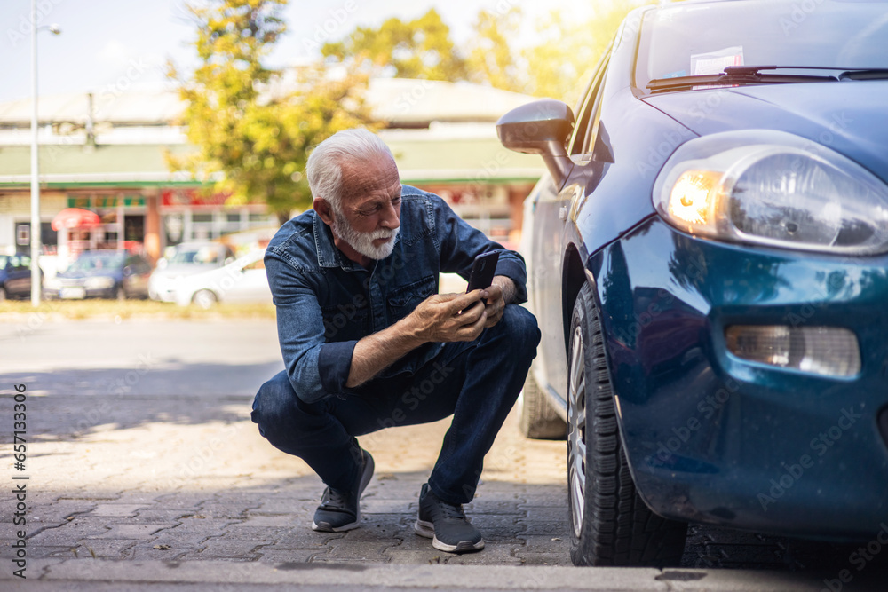 Portrait of a despair man crouching next to his car with flat tire ...