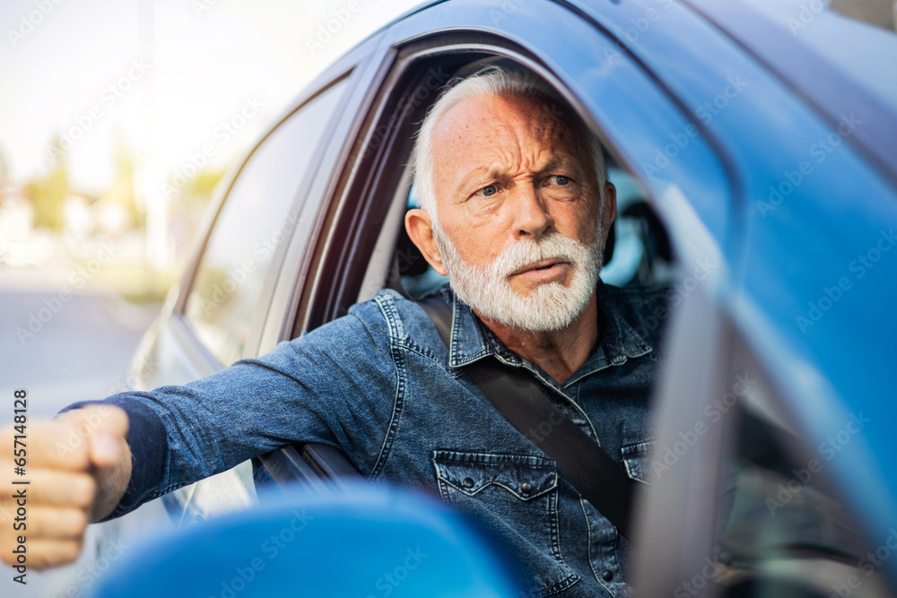 Angry man driving a car. The old men with an expression of displeasure ...