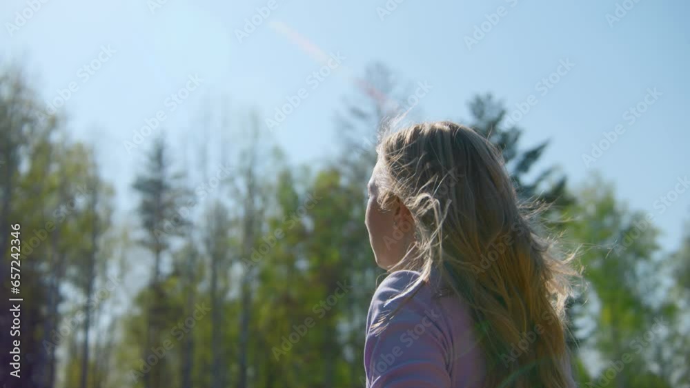 Beautiful woman throwing something out in nature. Stock footage. Rear ...
