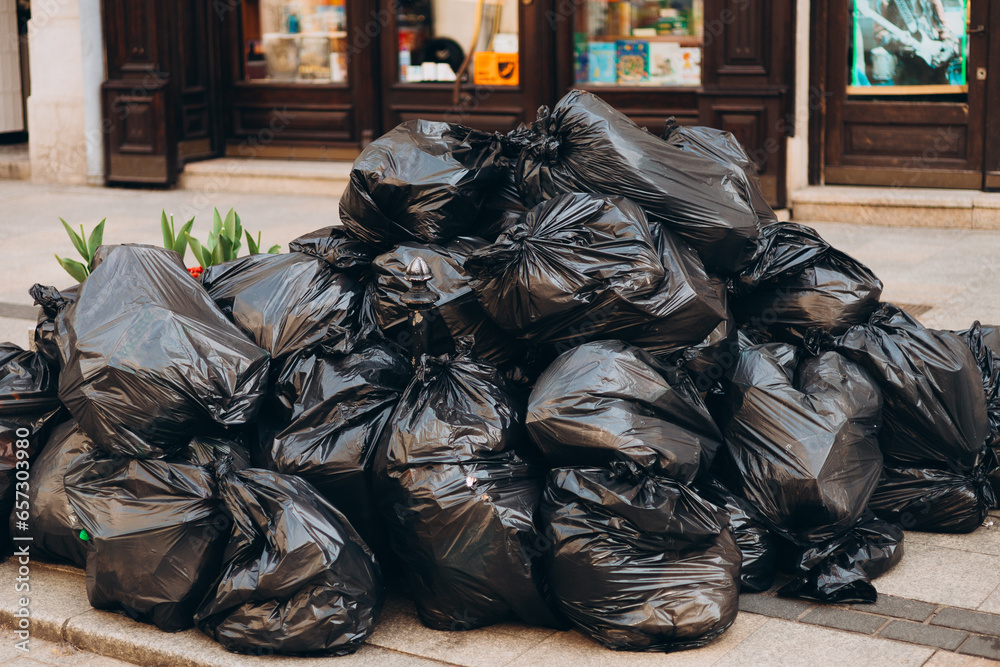 Pile of black garbage on the footpath at side road in big city ...