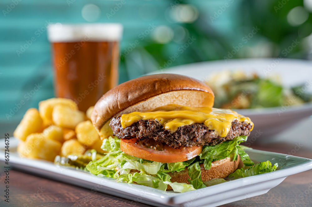 Fully loaded cheeseburger with tater tots and a beer. Stock Photo ...
