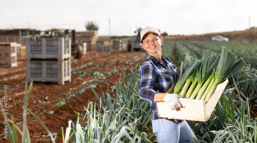Portrait of cheerful female farm worker posing at agricultural field ...