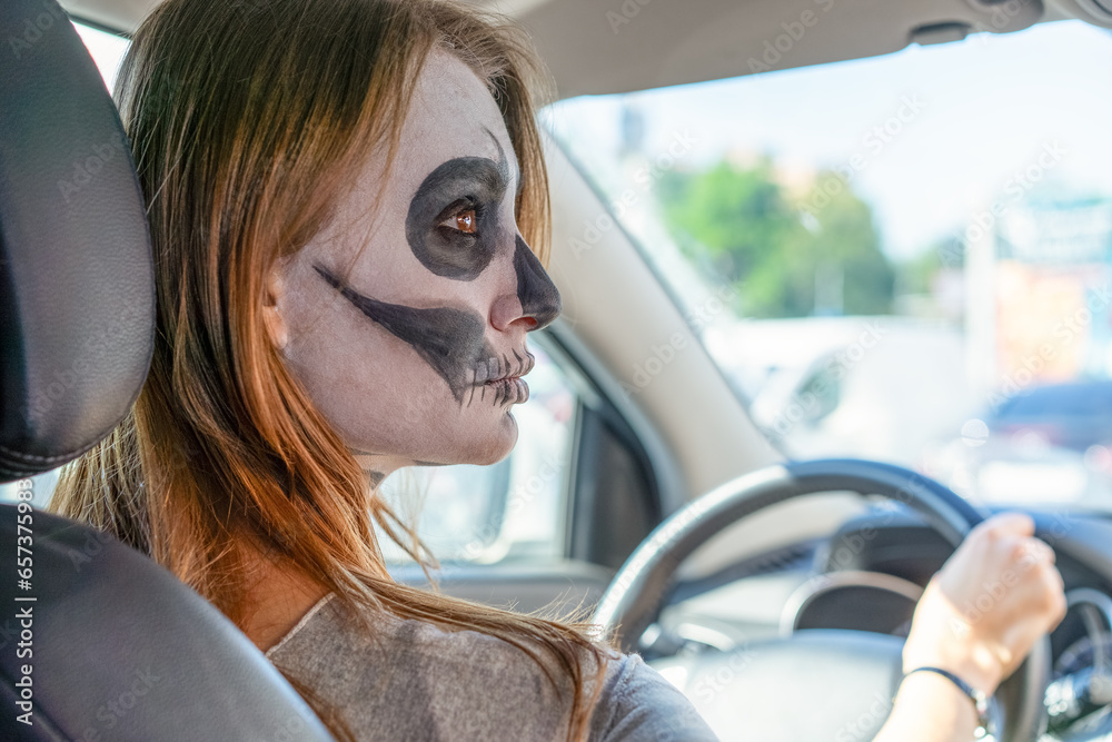 Profile of female driver with white death makeup rides in a car, holds ...