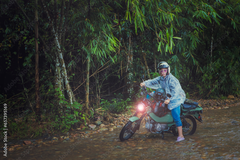 pretty woman riding small enduro motorcycle crossing shallow creek ...