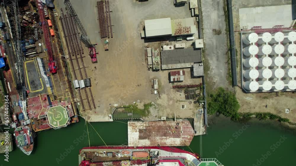 Vidéo Stock Overflying a shipyard with an oil tanker unloading its ...