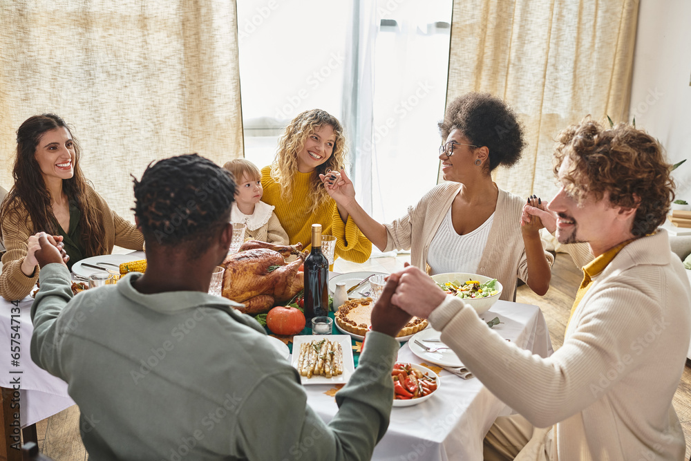 cheerful multiracial friends and family holding hands and praying at ...