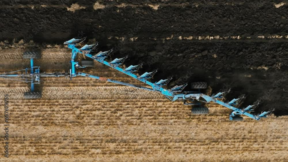 Reversible plow on support wheels moving behind a tractor in an field ...