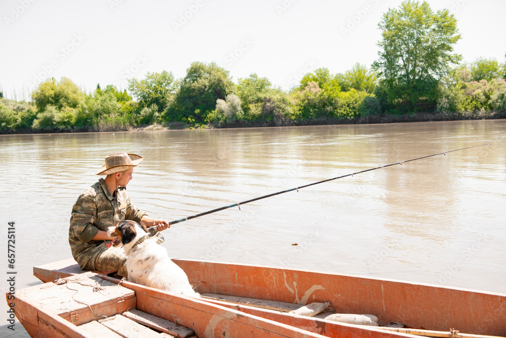 Tired male angler with setter dog, holding fishing rod, waiting for ...