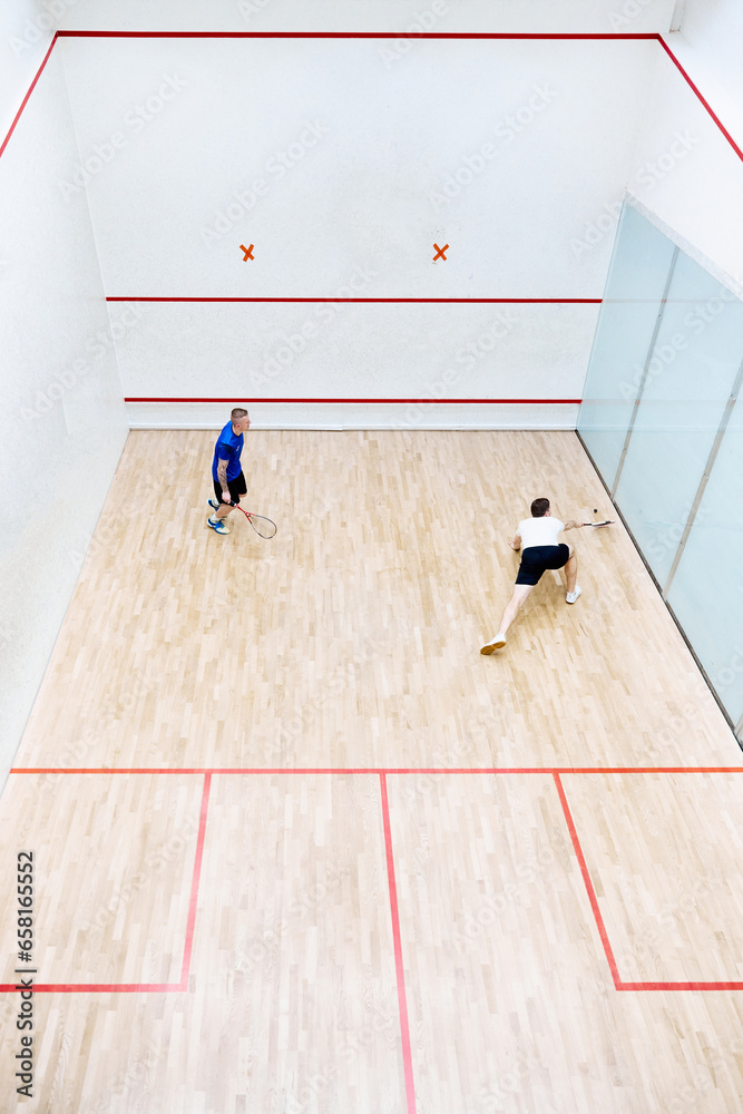 Top view of two young men, friends, sportsmen playing squash on squash ...