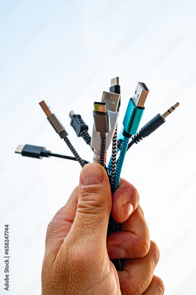 Hand holding various types of cables with USB plugs, evolution and ...