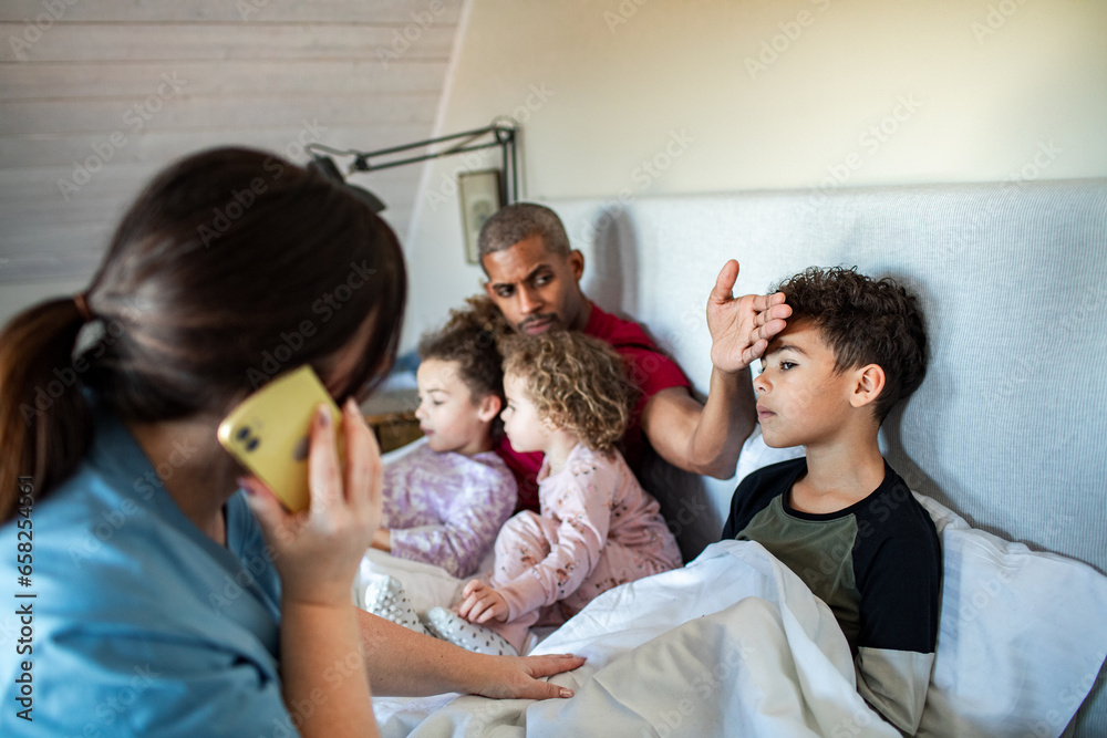 Concerned mother and father calling a doctor about their sons fever in ...