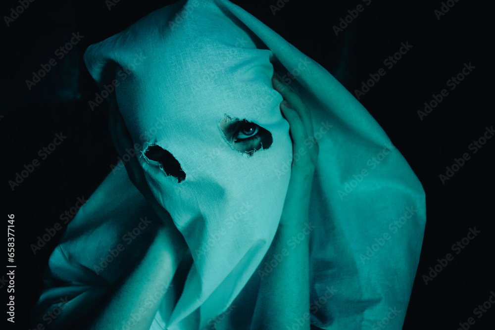 A woman wearing a white ghostly attire with eye-hole cutouts. It ...