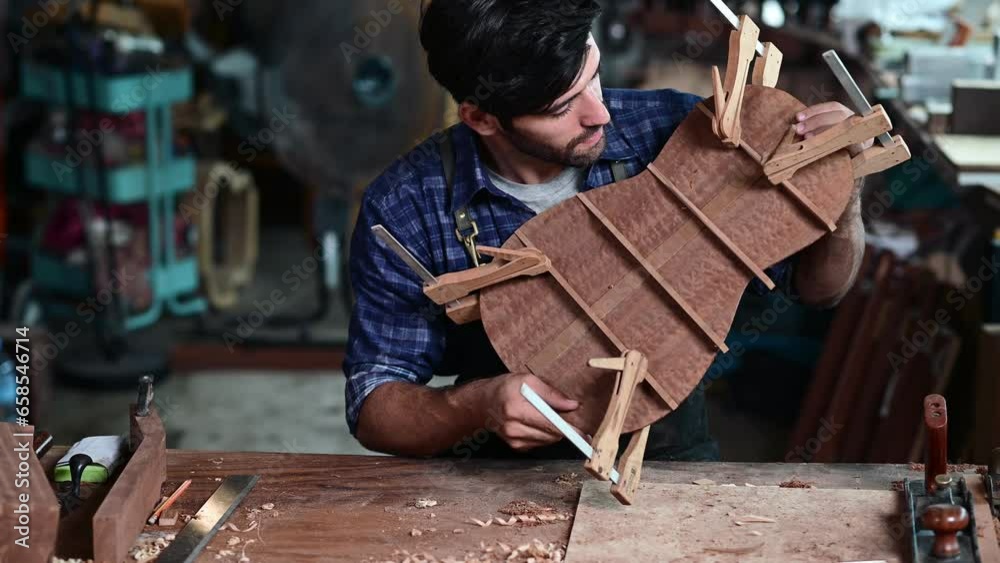 Luthier creating a guitar and using tools in a traditional, clamps on ...