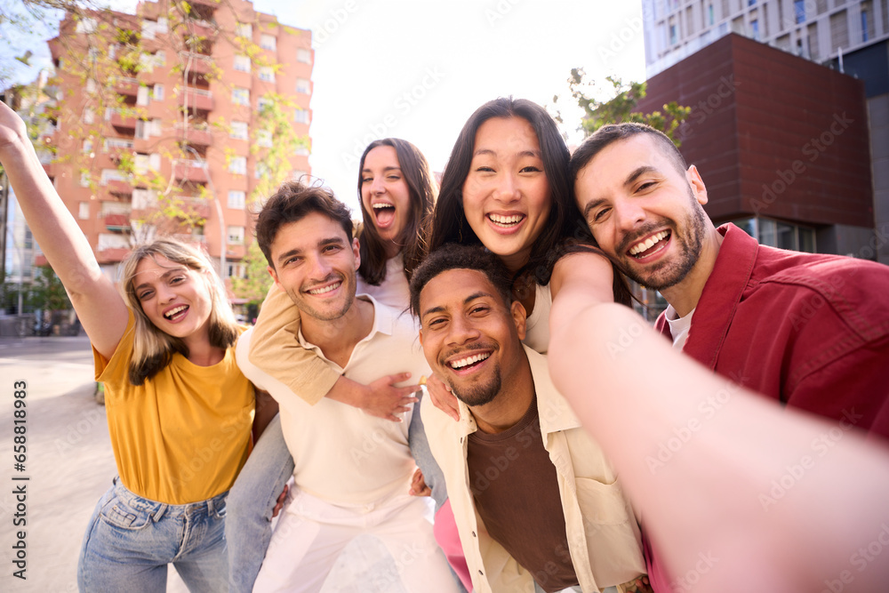 Big group of friends in piggyback taking selfie smiling at camera ...