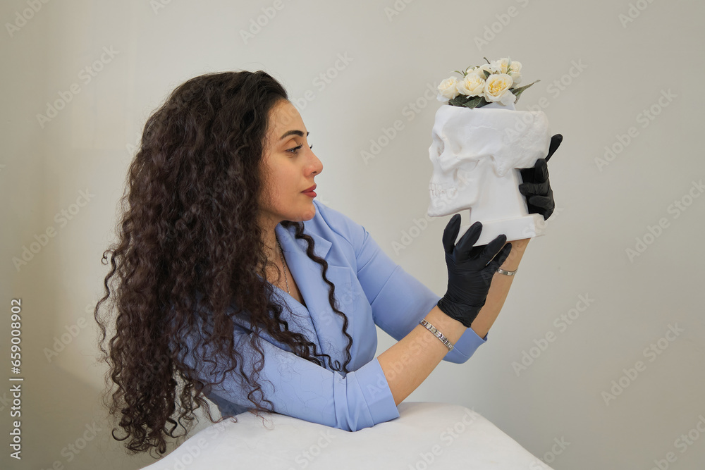 Dressed in a white suit with black gloves, she contemplates the skull ...