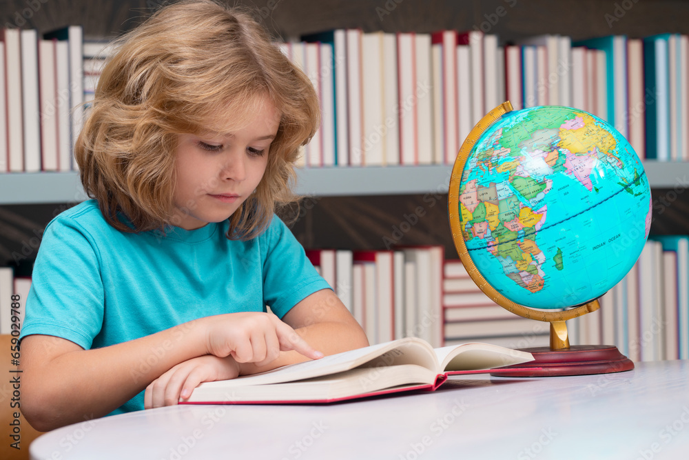 Cute pupil looking at globe in library at the elementary school. School ...
