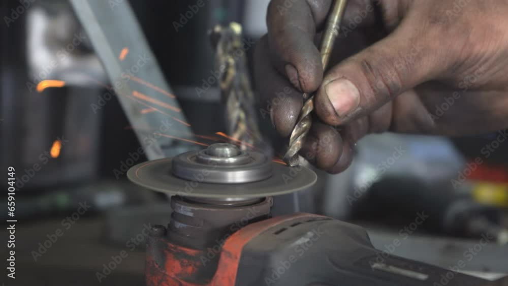 A master sharpens a drill using an emery disc. Sharpening a drill in a ...