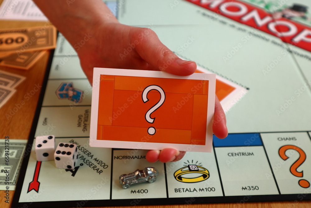 Monopoly board game. Close up over hand holding one game card called ...