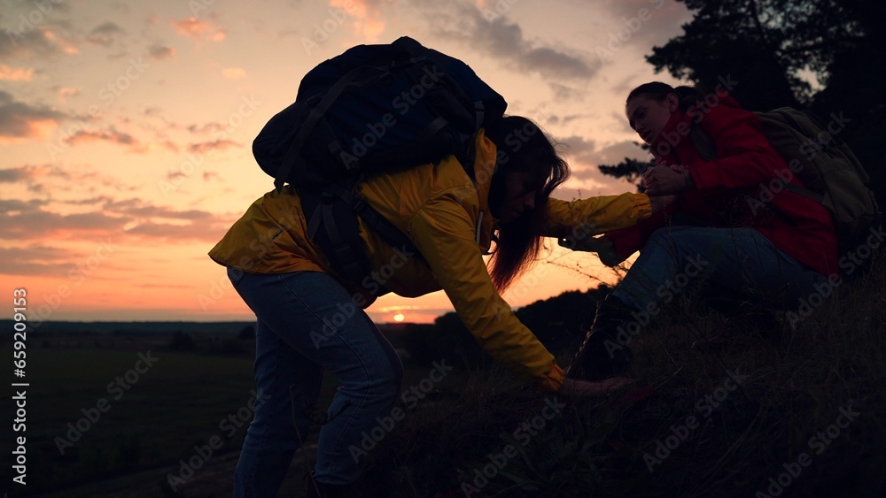 Travelers give each other helping hand, climbing to top of mountain ...