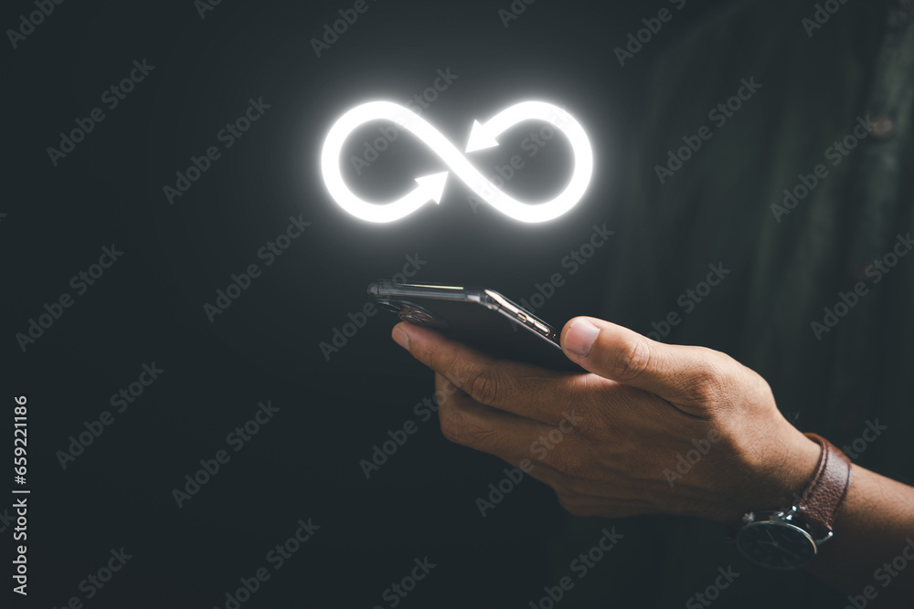 Businessman displays smartphone with infinity symbol, indicating ...