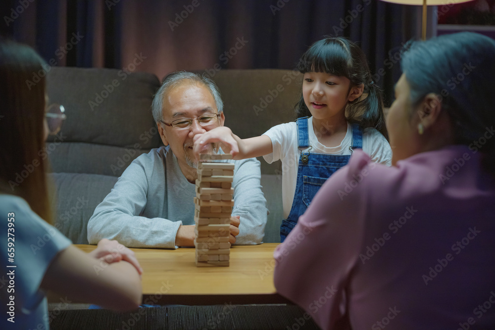 Happy grandparents Asian family enjoy playing toy block with little daughter and mother together ...