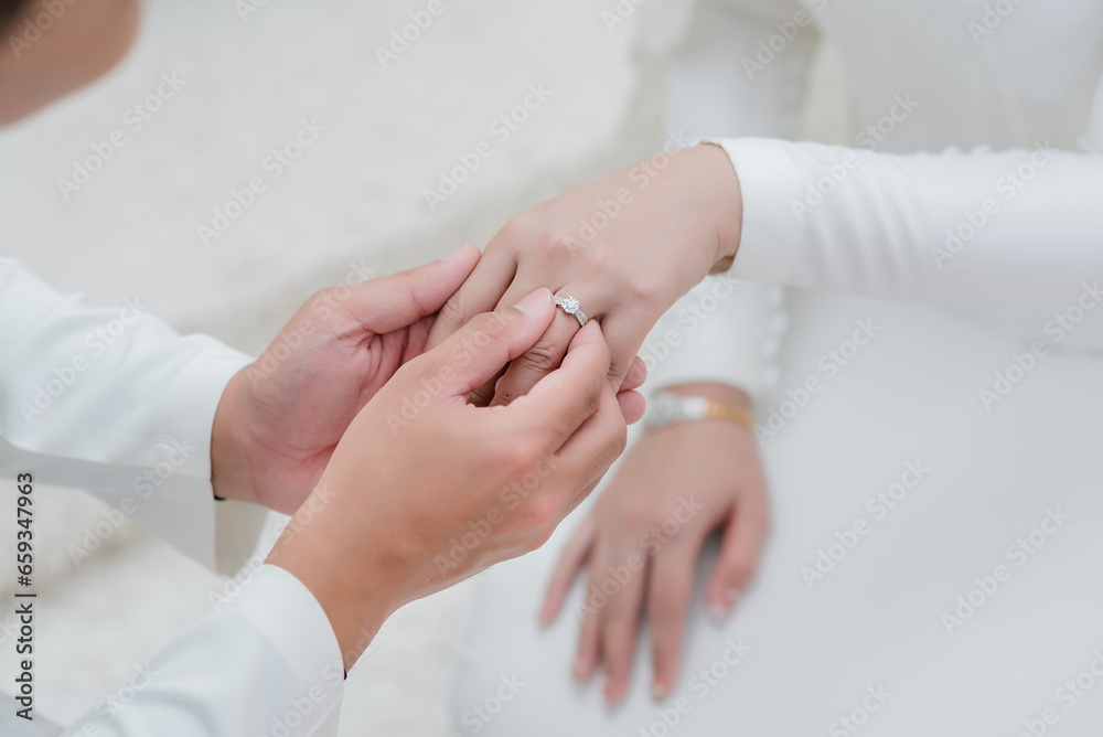 Close up hand groom wearing wedding rings to left finger of bride ...