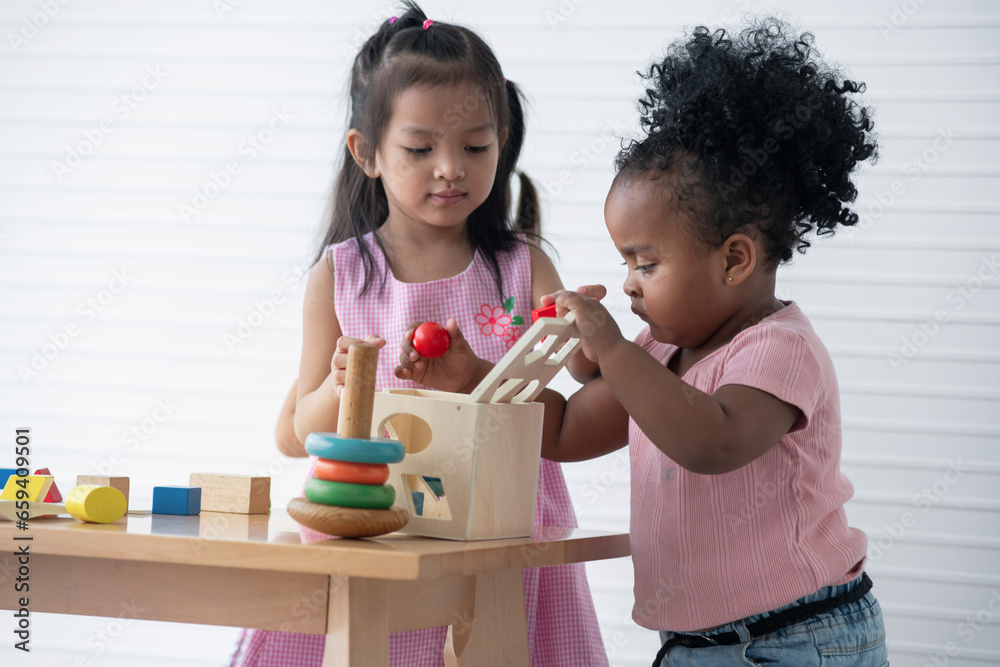 Two girls of different nationalities play with educational toys ...