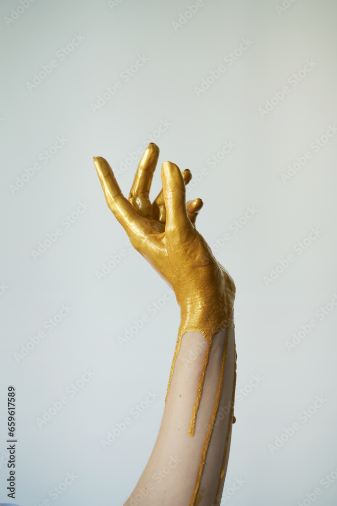The hand is in gold acrylic paint, the paint covers the hand like a ...
