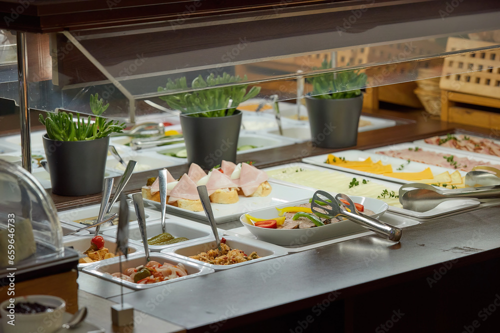 Breakfast in hotel, illuminated table with different dishes, fruits and ...