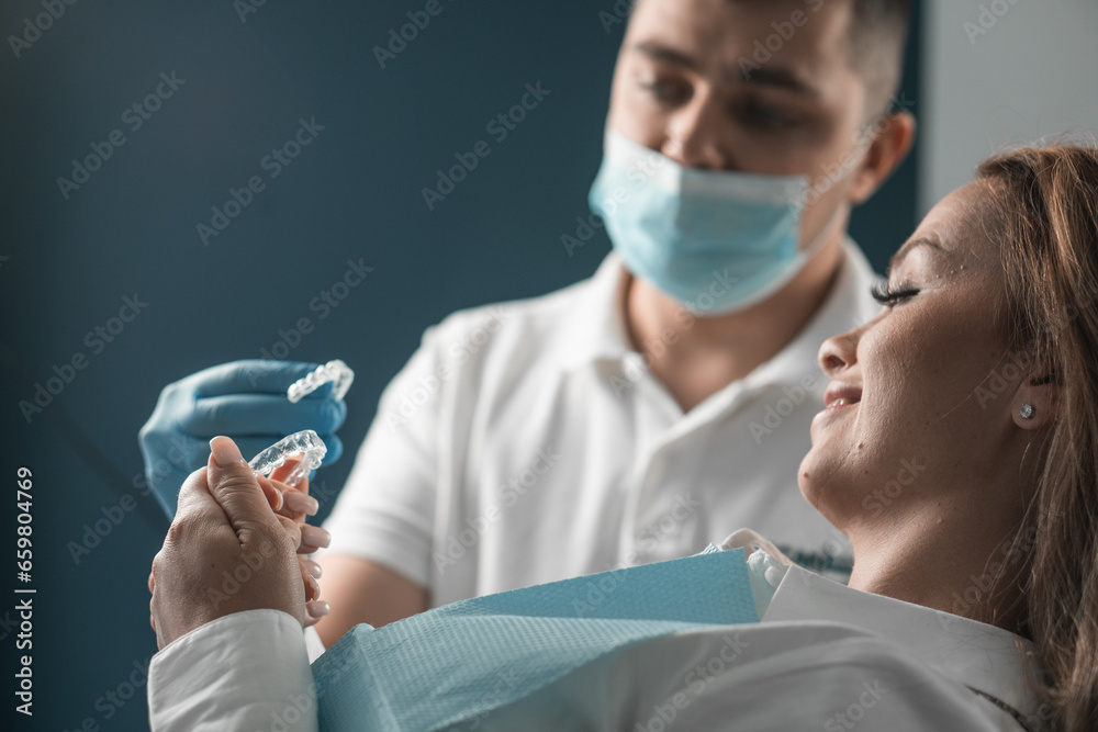 A dentist shows veneers to female patient as method correcting teeth ...