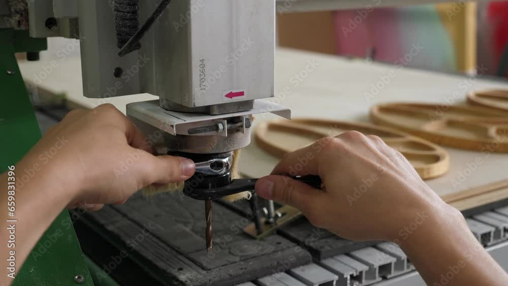 A man changes a drill bit on an industrial wood carving machine ...