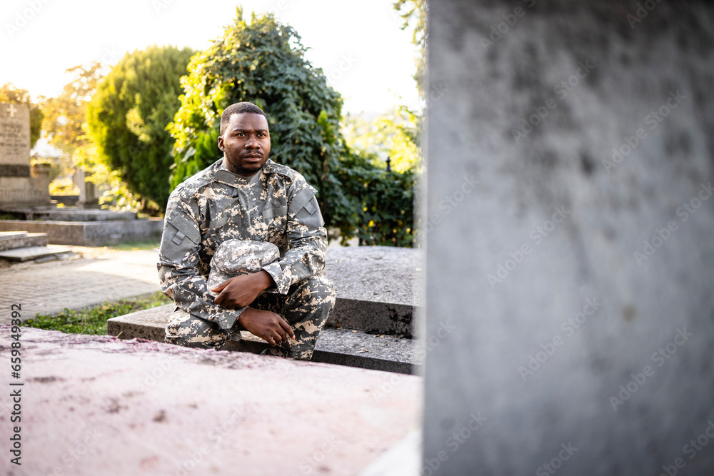 Sad moment of soldier in uniform kneeling by the grave of his fallen ...