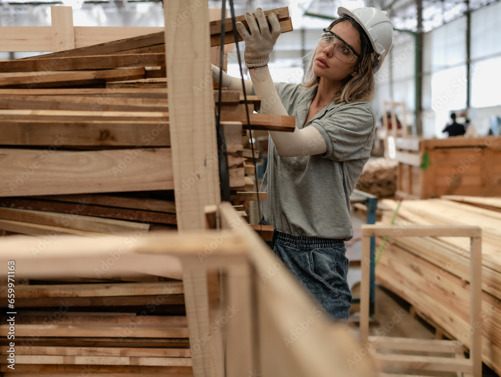 Confident female worker working in lumber warehouse of wooden furniture ...