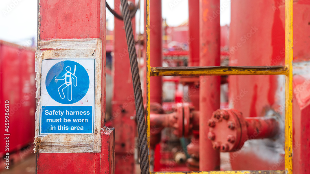 Safety harness PPE requirement caution sign wihch is installed on the ...