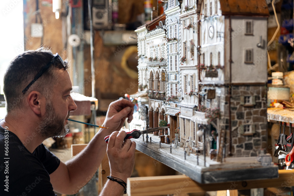 Modeller man working at scale model of miniature building in his ...