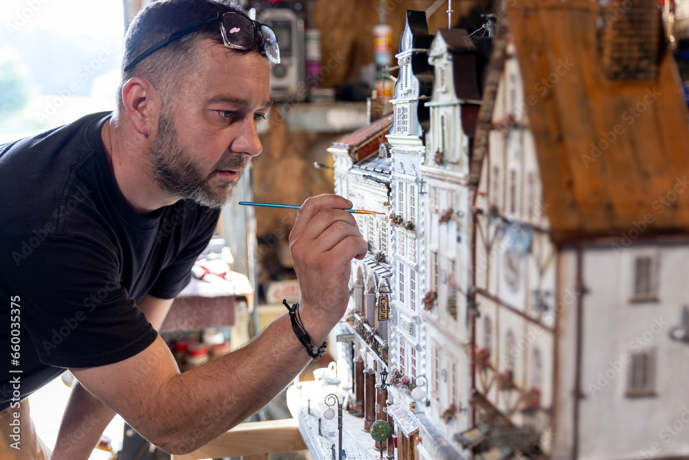 Modeller man working at scale model of miniature building in his ...