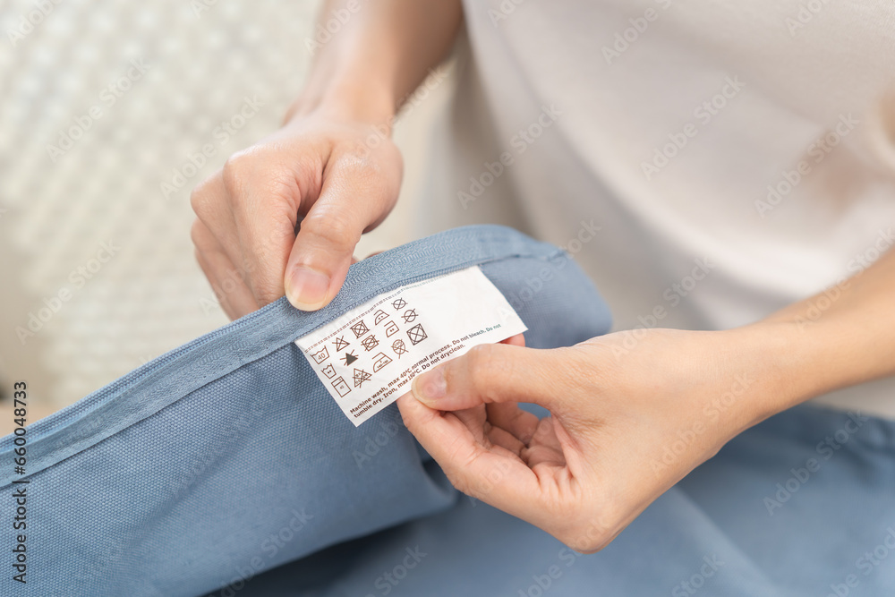 Housewife young maid woman hand holding clothing label care on textile ...