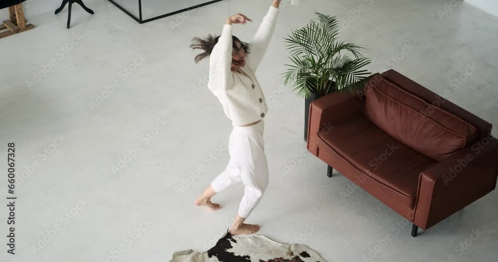 Dynamic woman fills her living room with boundless energy, dancing with ...