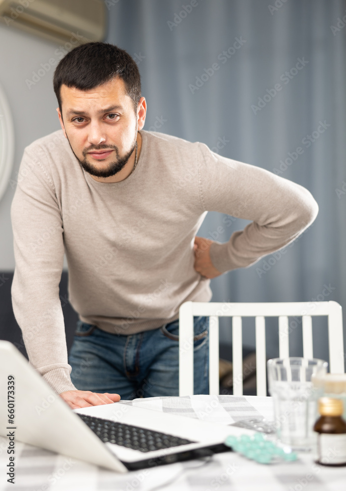 Bending bearded guy with his hand on loins feeling acute pain in back ...