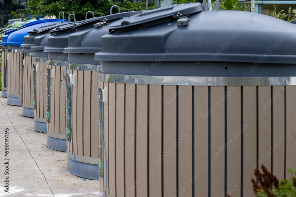 A row of industrial round compost bins. The containers are black ...