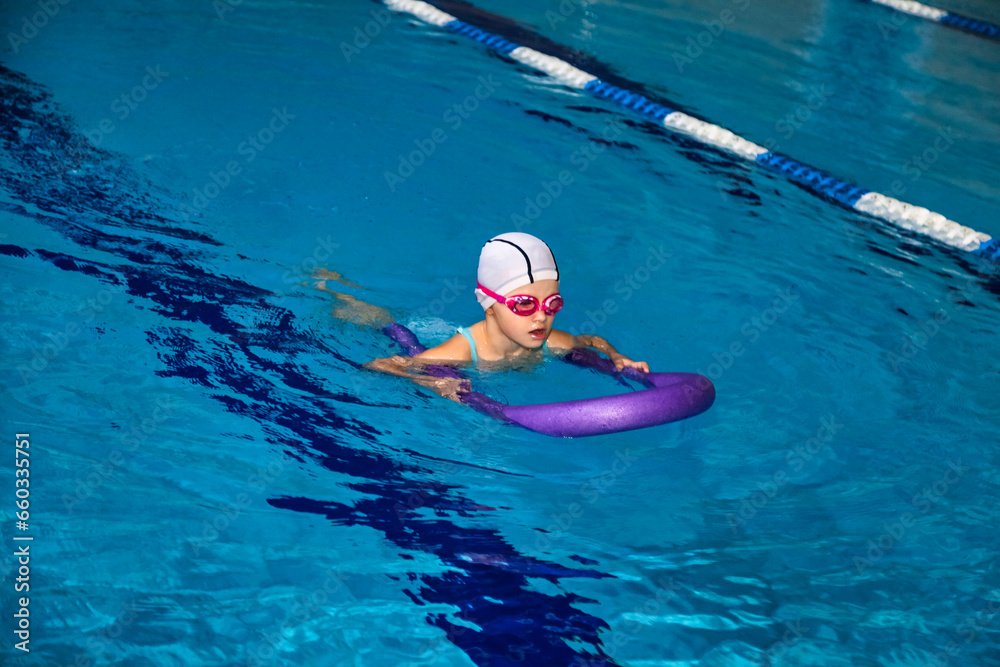 Kid girl 5-6 year old with swimming bobber exercising in pool, learning ...