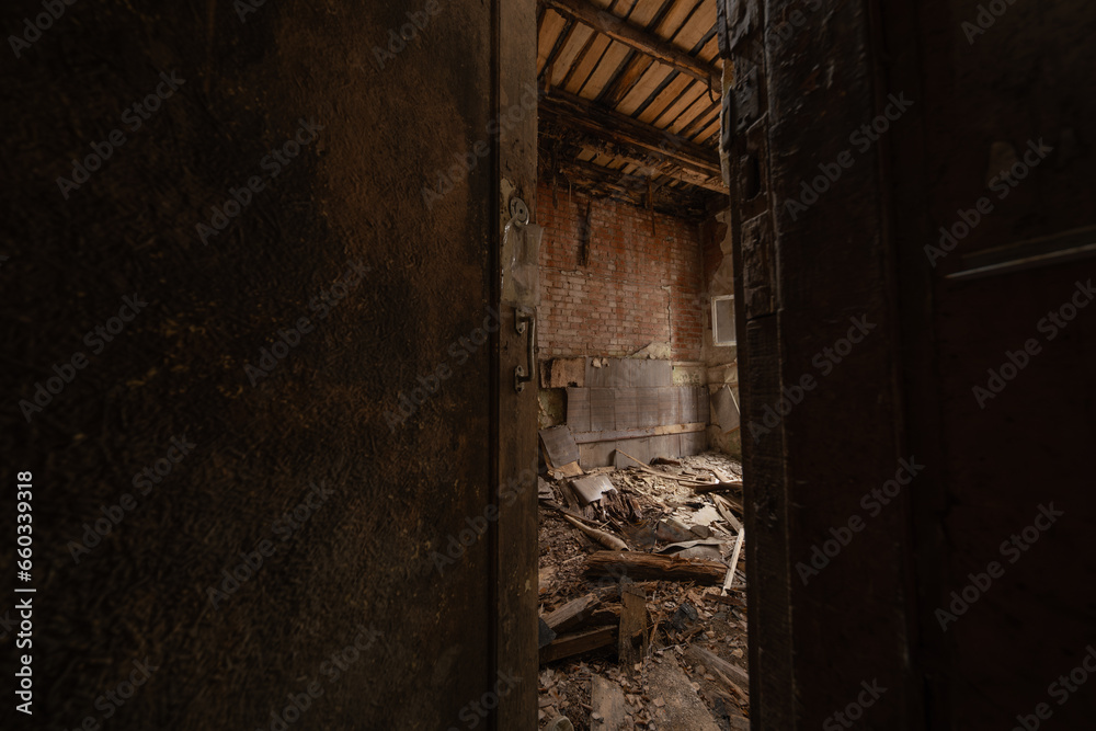 Half opened wooden door leading to weathered destroyed room of ...